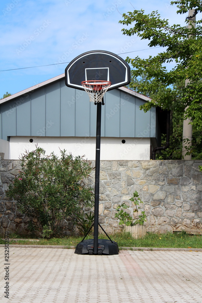 Amateur metal and plastic basketball hoop mounted on stone tiles ...