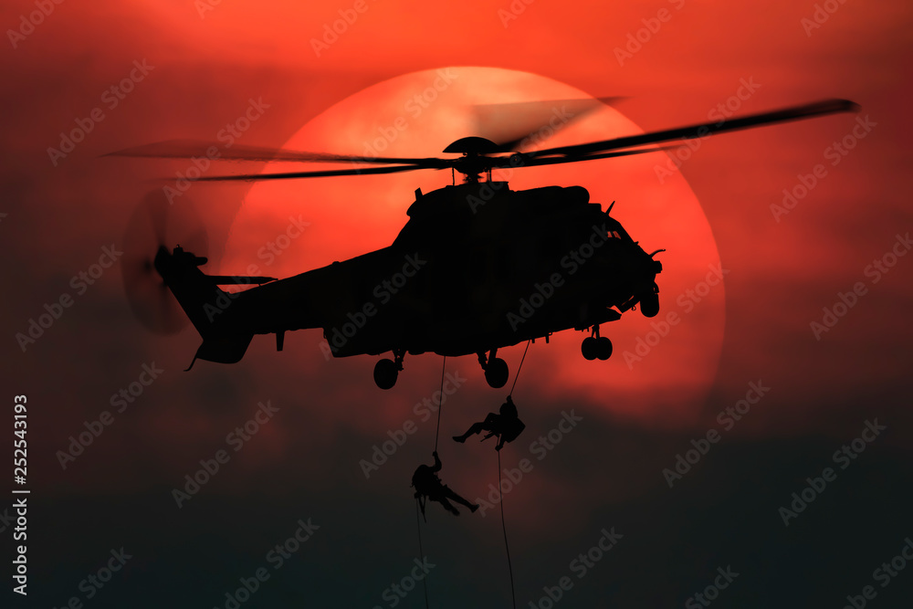 Shot of rescue helicopter hopping in front of the big sun with two ...