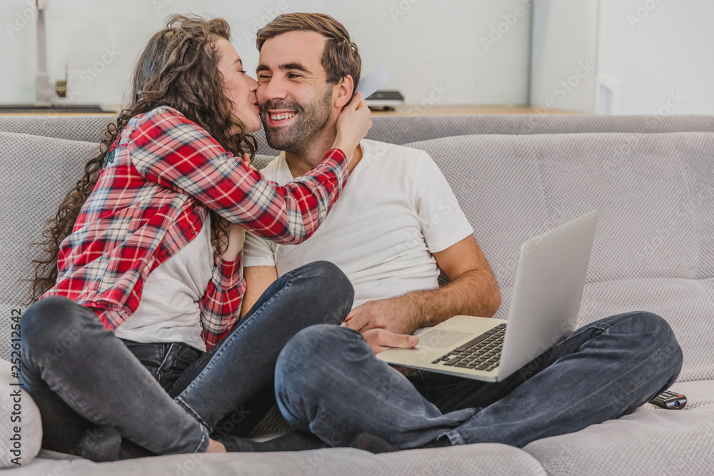 Smiling young couple, enjoying the time spent at the computer, sitting ...