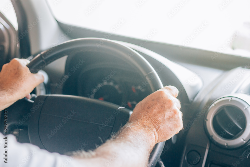 Man driving the car with both hands at the wheel. It has spots on the ...
