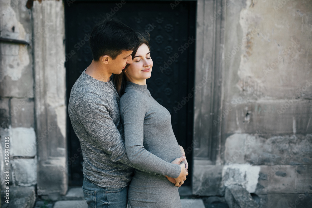 Stylish pregnant couple holding hands on baby bump and relaxing in ...