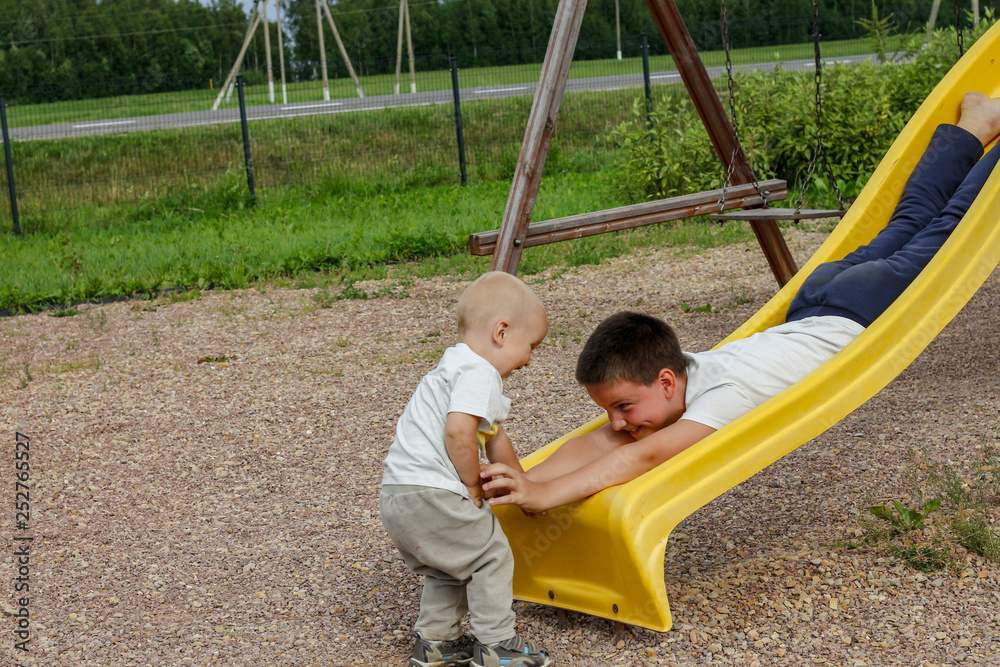 children play on the playground, one boy slides upside down and tickles ...