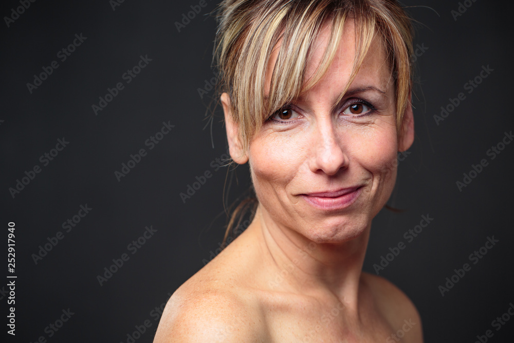 Portrait of a smiling middle aged caucasian woman against dark ...