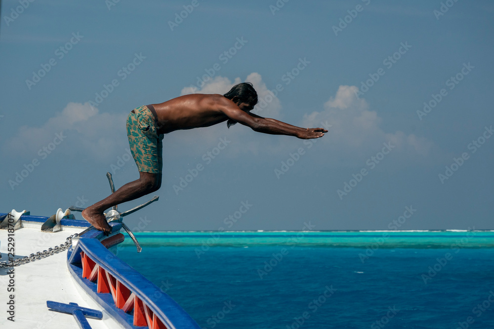 maldivian man diving from boat in blue ocean Stock Photo | Adobe Stock