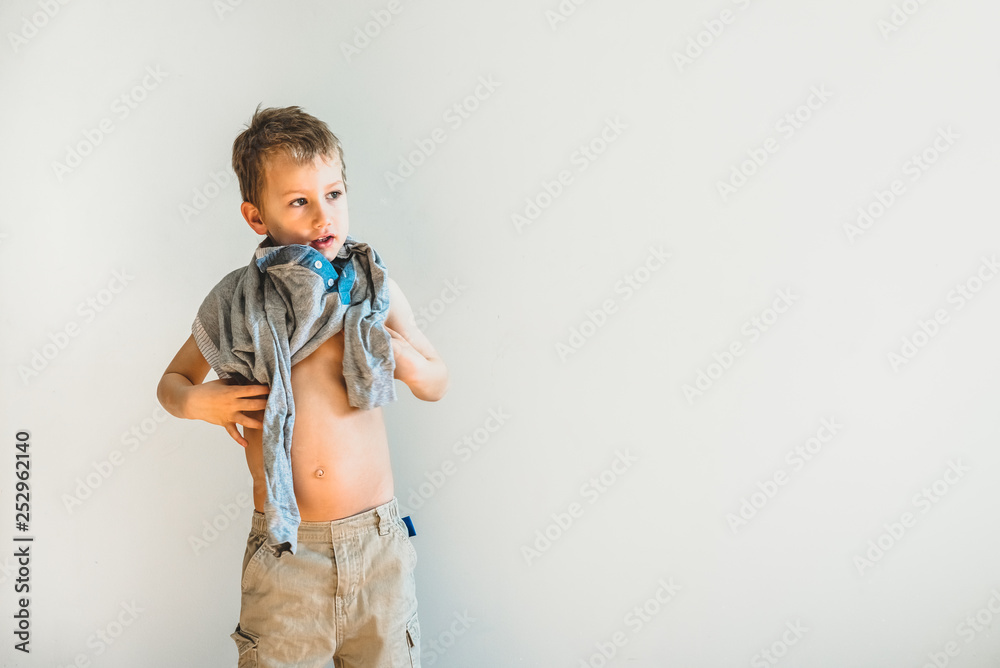 Child trying to take off his shirt and undress on his own. Stock Photo ...