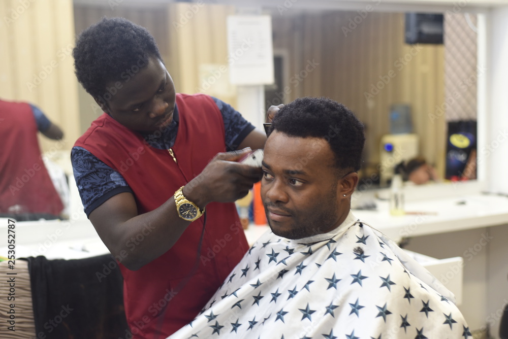 Black man in the african barbershop. Cute black man makes a haircut in ...