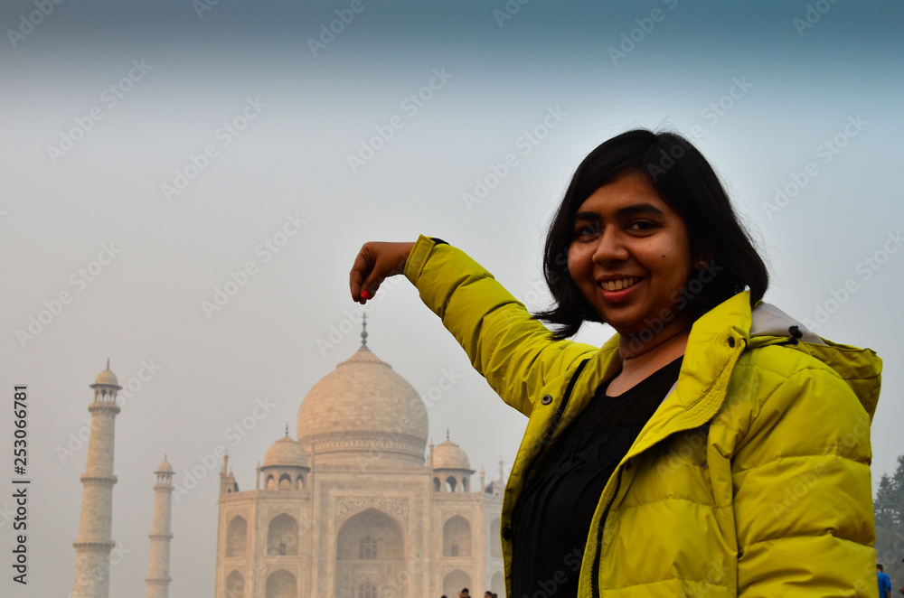 Young Indian female tourist posing in front of Taj Mahal. Posing as if ...