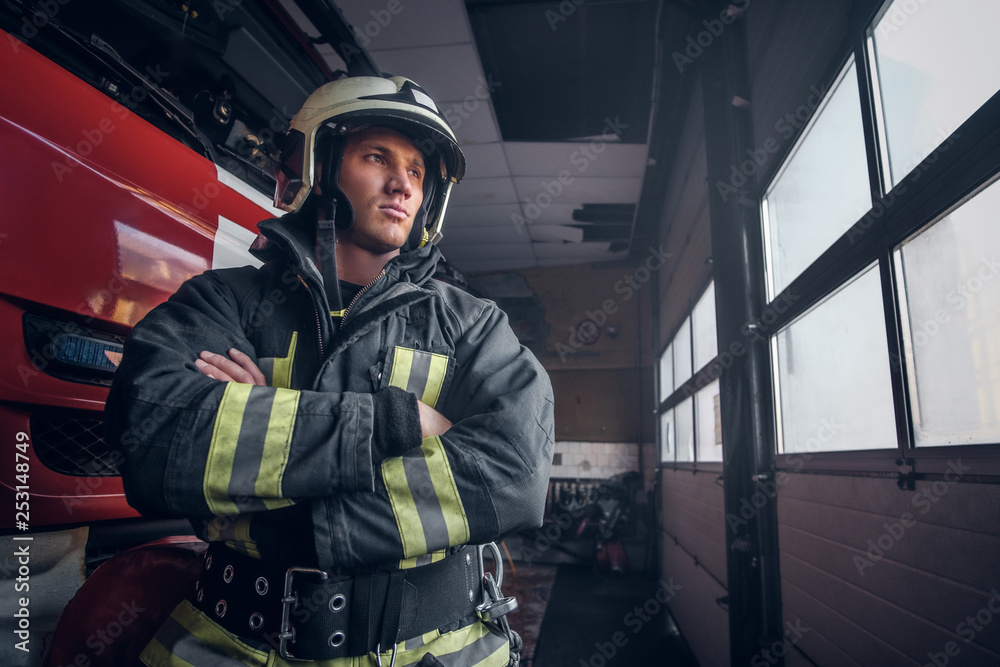 A brave fireman wearing protective uniform standing next to a fire ...