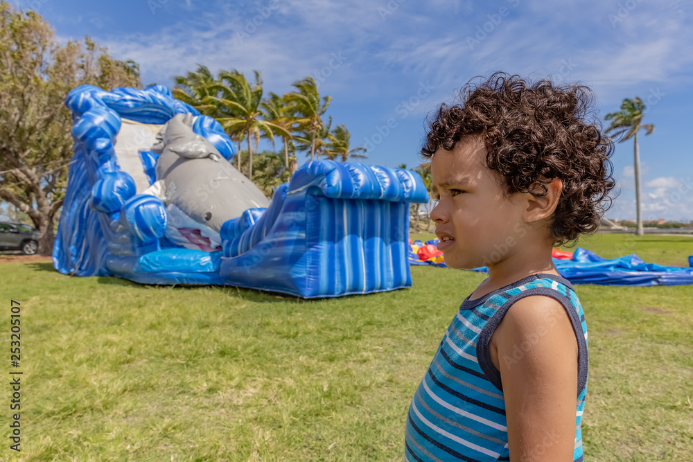 A profiled toddler stands very still with a confused look while the ...