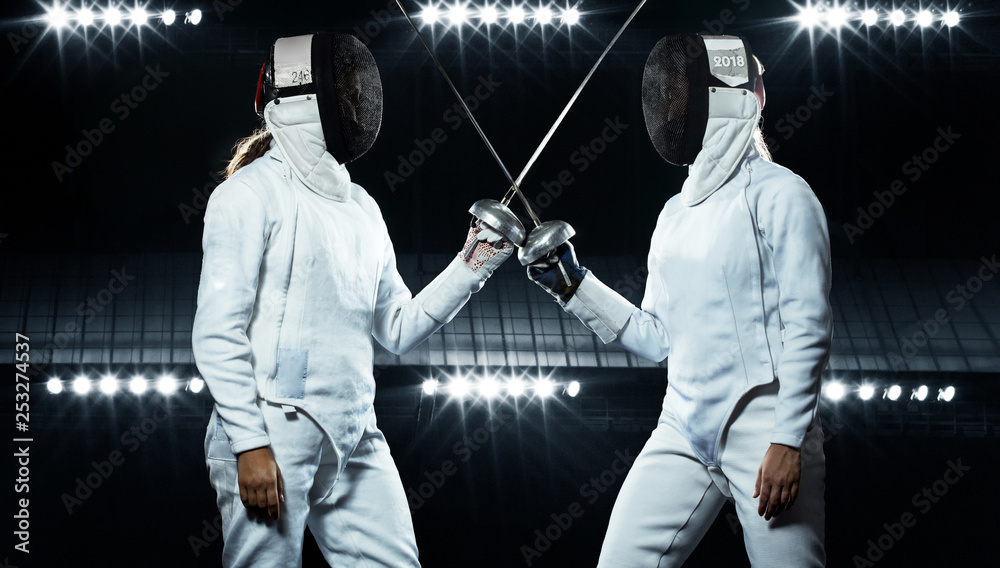 Young fencer athlete wearing mask and white fencing costume. holding the sword on black ...