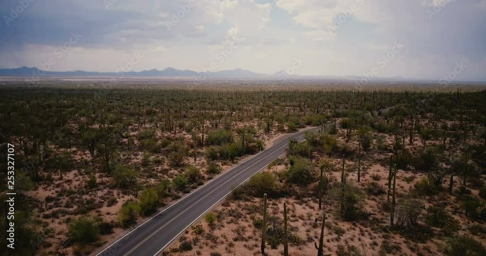 Drone panning left above scenic winding desert road in large ...