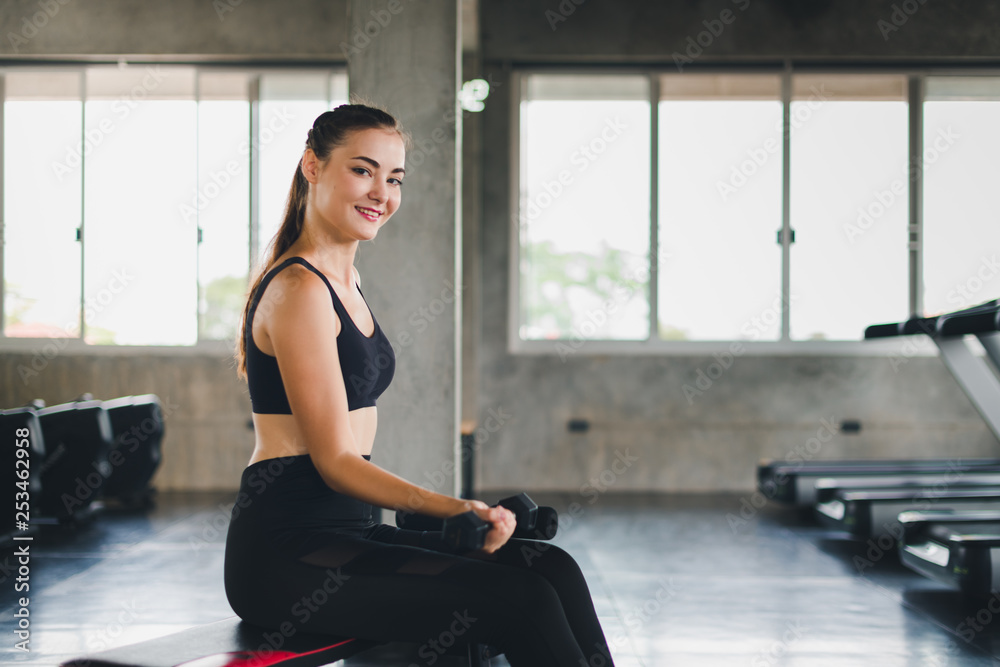 Beautiful girl caucasian is exercising with lifting dumbbell in the gym ...