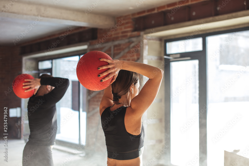 athletic sportsman and sportswoman doing exercises with medicine balls ...