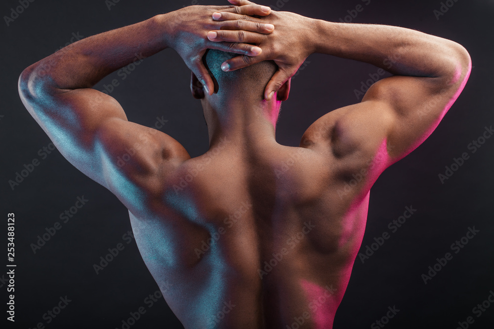 Muscular man African bodybuilder, back view. Man posing on a black ...