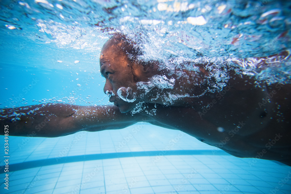 Underwater image of a male swimmer diving and swimming in a swimming ...