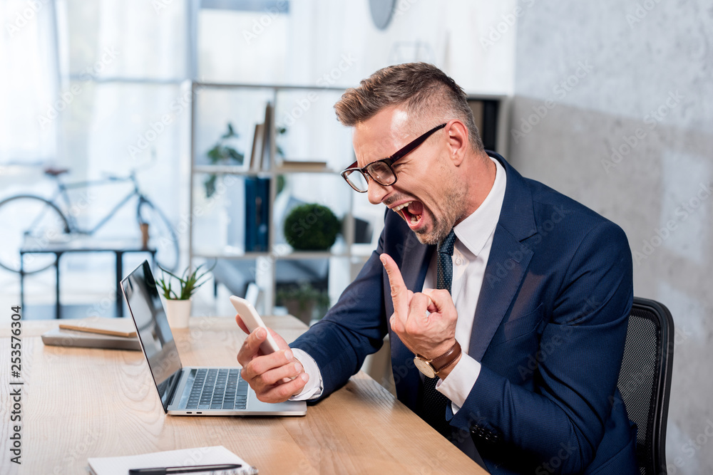 emotional businessman in glasses and suit screaming while holding ...