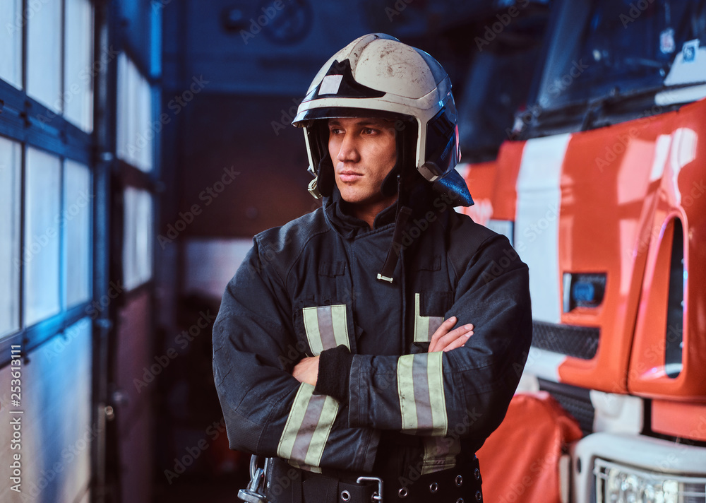 A brave fireman wearing protective uniform standing next to a fire ...