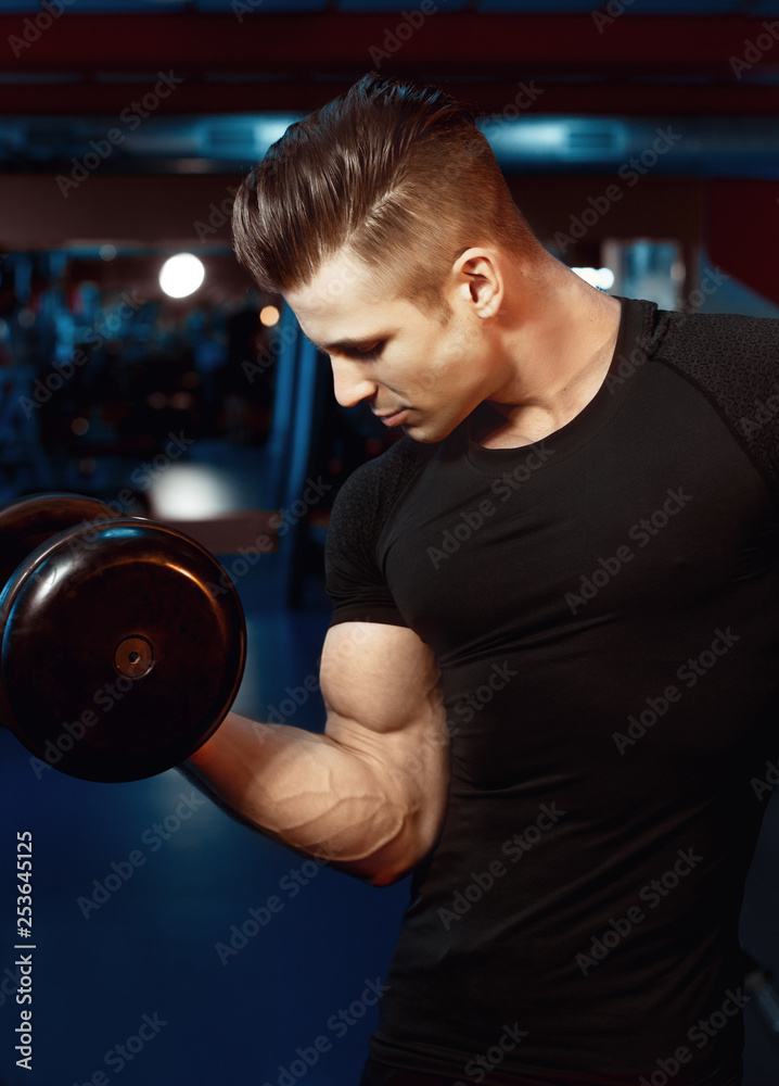 Muscular model sports young man exercising in gym with dumbbell ...