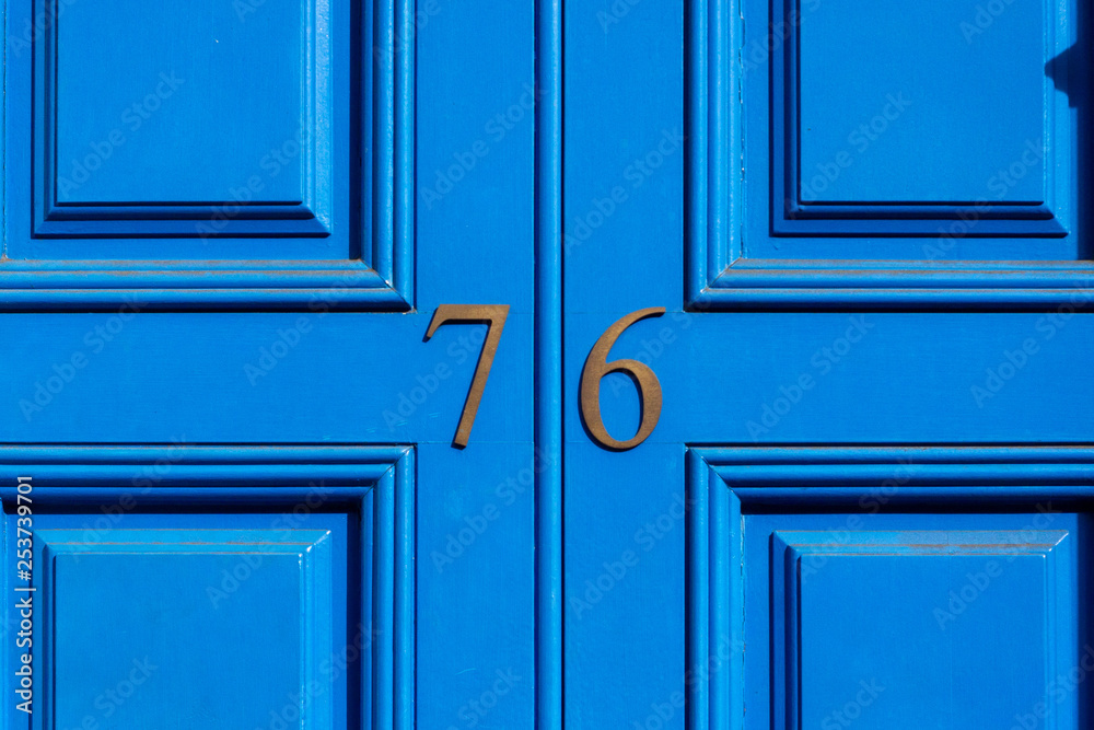 House number 76, with the seventy-six in bronze numerals on a blue ...