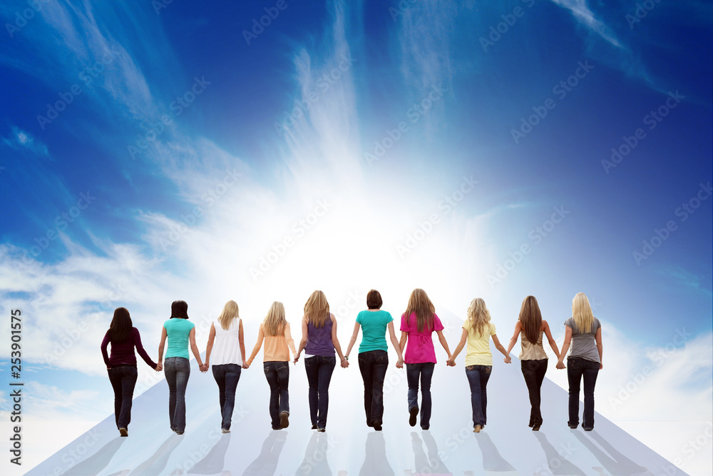 Ten young women walking hand in hand towards a bright blue sky ...