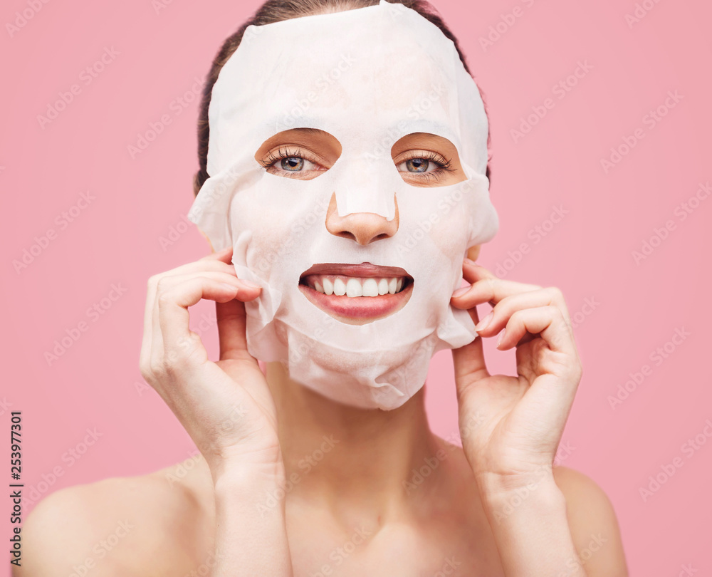 Beautiful young woman is applying a cosmetic tissue mask on a face on a ...