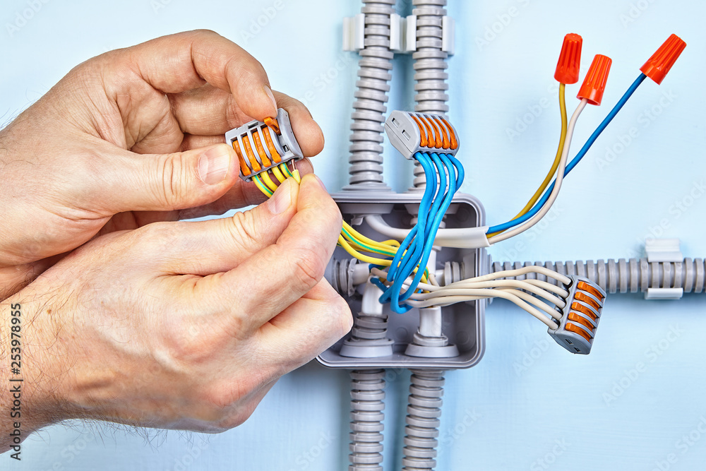 Worker is installing surface mounted wiring. Stock Photo | Adobe Stock