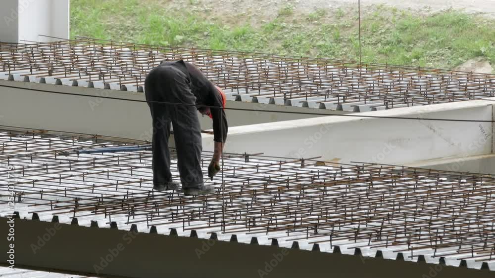 A worker installs rebar for formwork reinforcement on a commercial ...