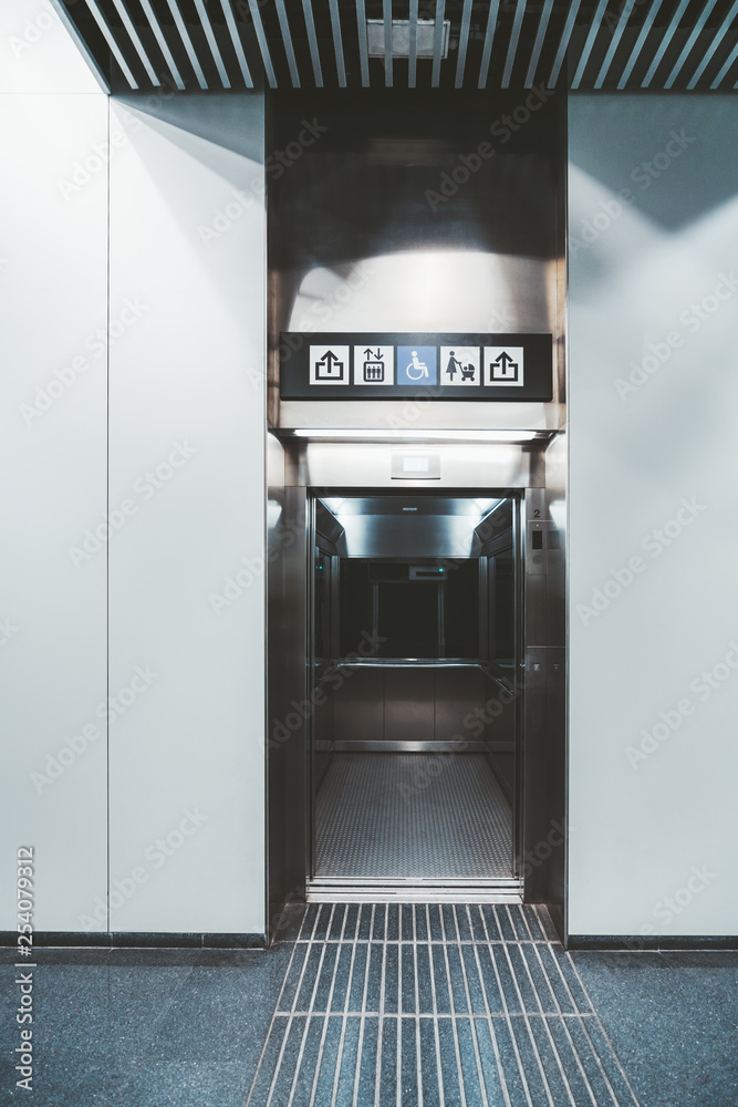Vertical view of a modern chrome elevator with opened doors indoors of ...