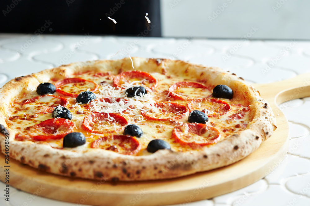 Grating cheese on pepperoni pizza Stock Photo | Adobe Stock