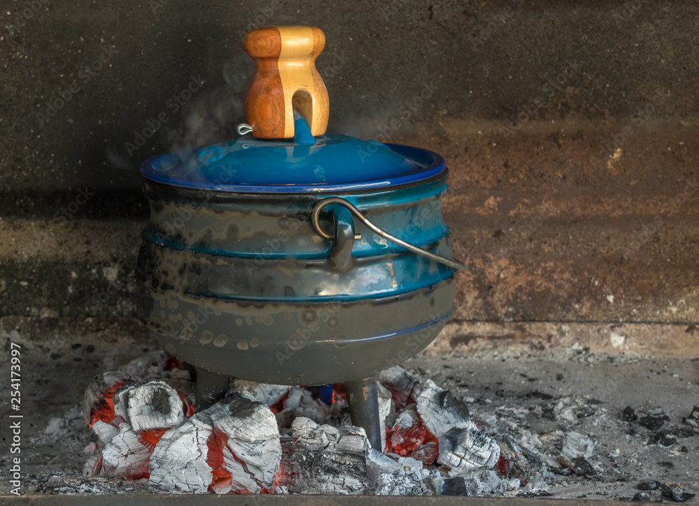 A traditional South African meat and vegetable dish being prepared in a ...
