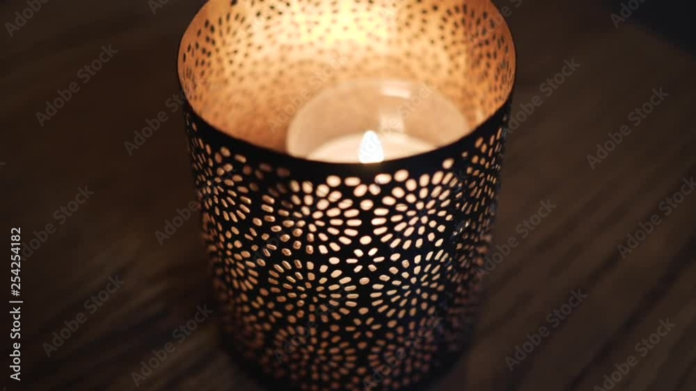 A burning candle from above which is inside a holder, an old bar with ...