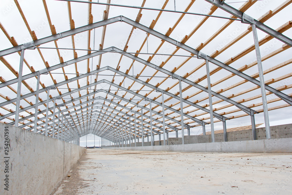 The construction of the new barn. Wooden beams on a metal frame ...