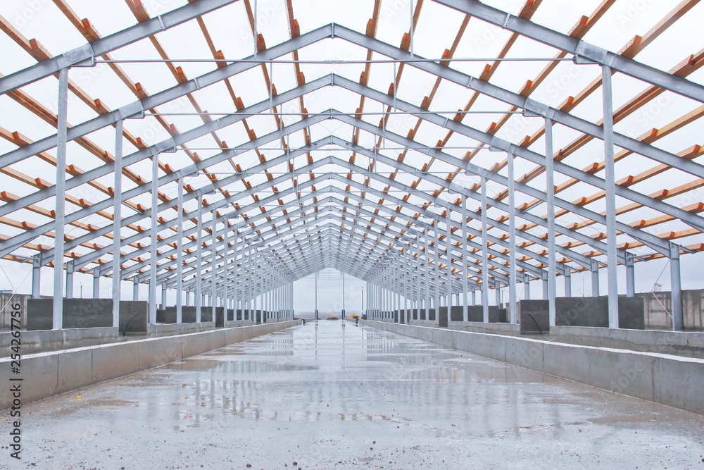 The construction of the new barn. Wooden beams on a metal frame ...