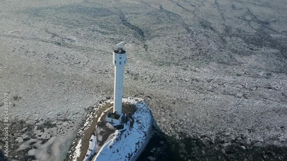 Cinematic drone / aerial footage circling a tower over a frozen lake ...