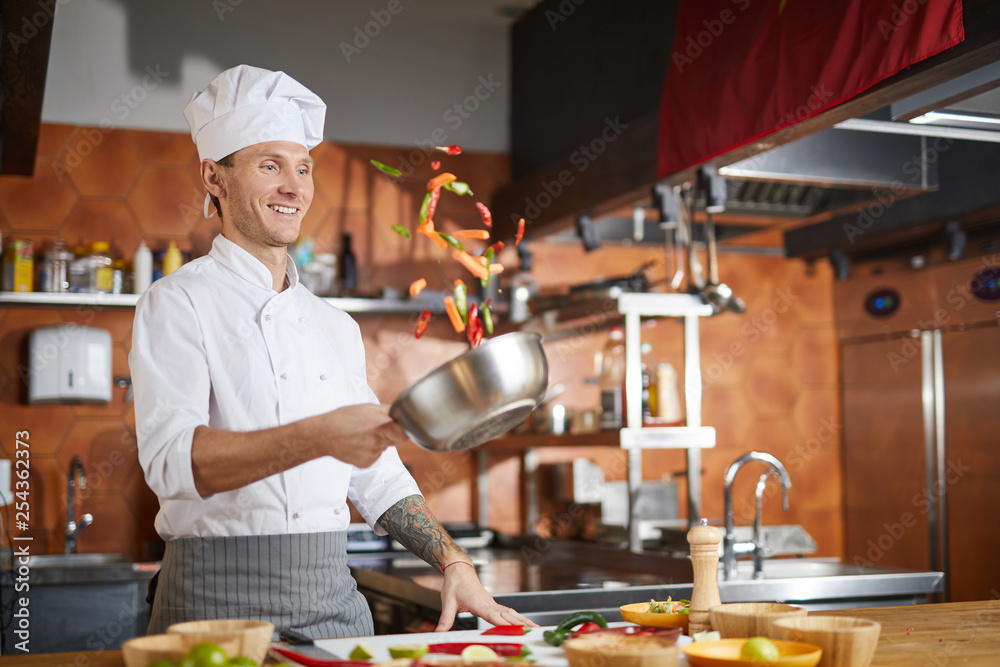 Waist up portrait of handsome professional chef cooking in restaurant ...