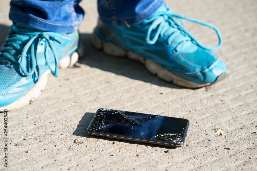 cellphone with broken screen is on the concrete floor after falling ...