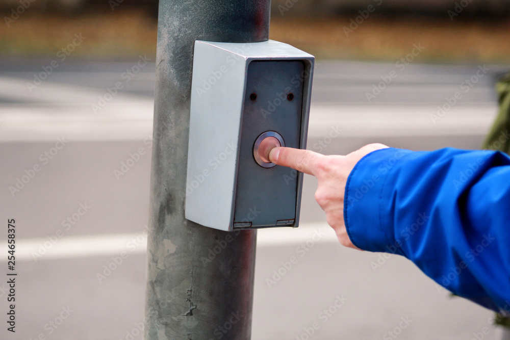 Portrait of male hand pressing button for crossing street on crosswalk ...