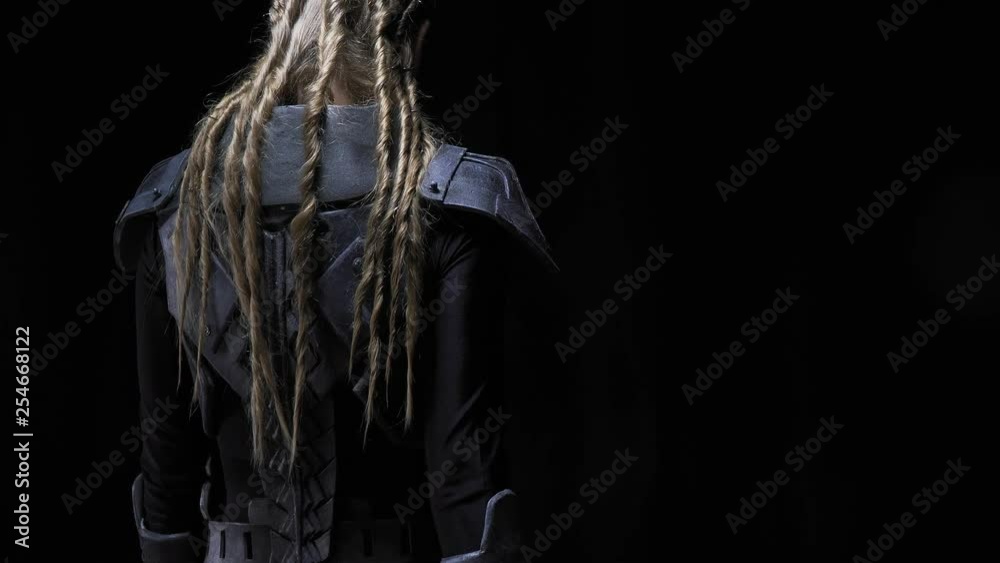 Creepy alien with dreadlocks and armor is quickly turning and looking ...