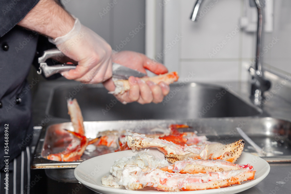 Cook chef is carving fresh red big boiled prepared blue kamchatka crab ...