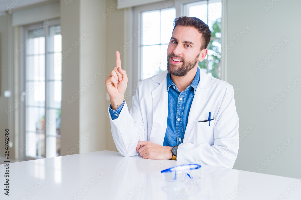 Handsome scientist man wearing white robe and safety glasses with a big ...