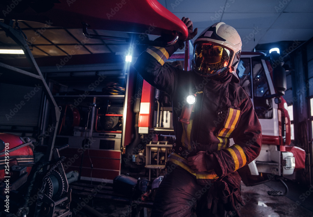 Fireman wearing a protective uniform with flashlight included working ...