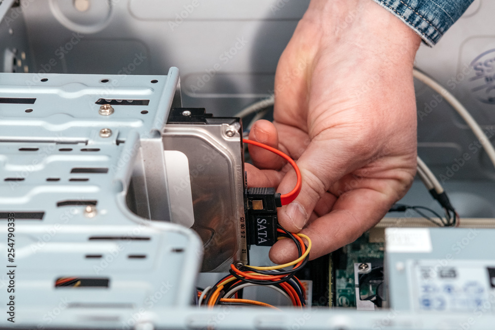 Hand of man plugging SATA (Serial AT Attachment, Serial ATA) data cable ...