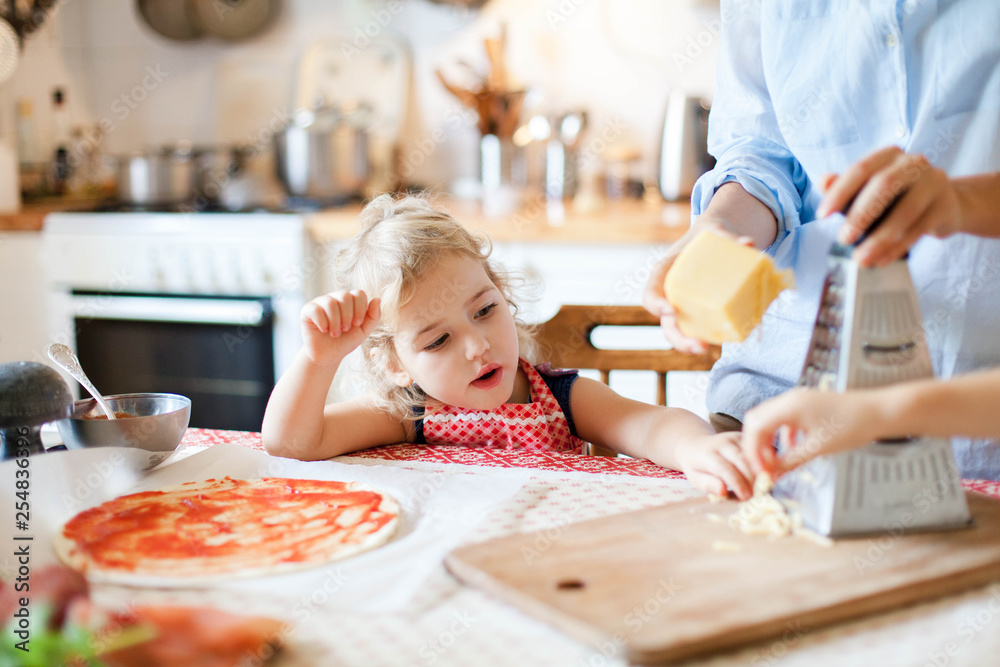 Funny child gourmet is eating and tasting cheese. Family are cooking ...