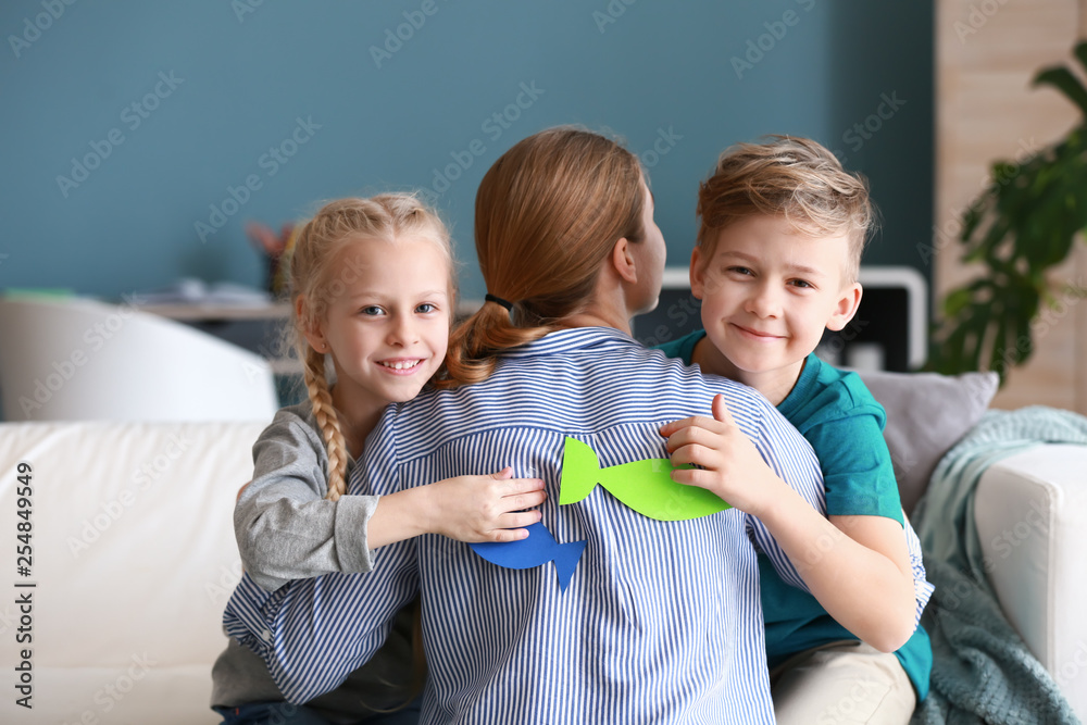 Little children sticking paper fish to their mother's back. April fools ...