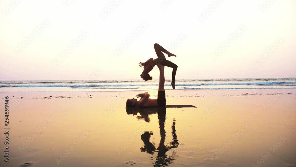 Silhouette of fit sporty couple practicing acrobatic yoga with partner ...