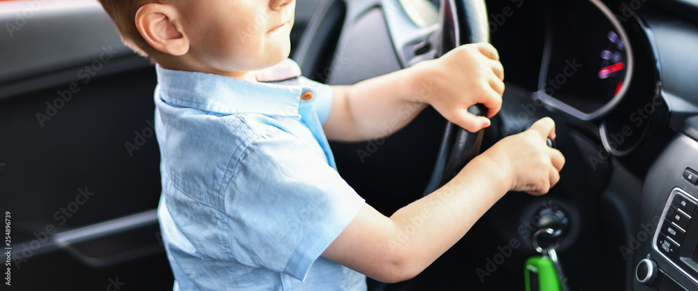 Banner. Little blond boy in a blue shirt driving a big car, switches ...