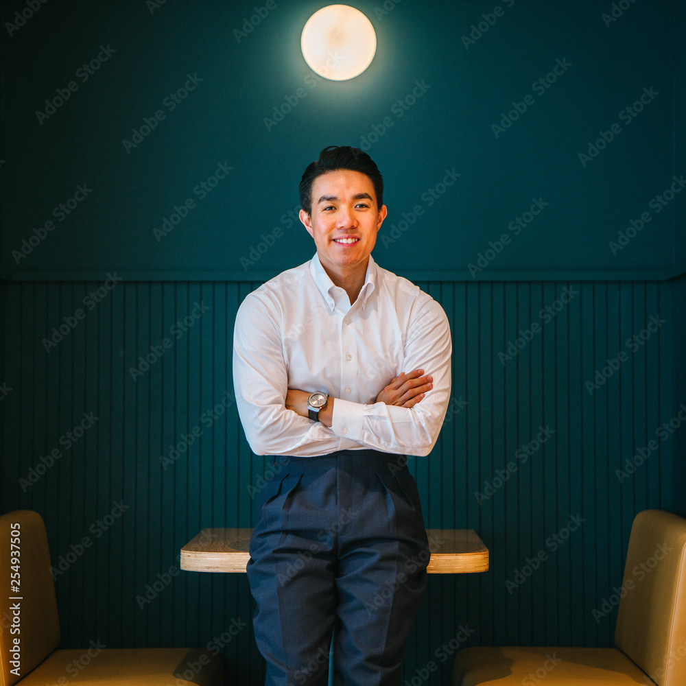 Portrait of a professional Chinese Asian man leans against a table and ...