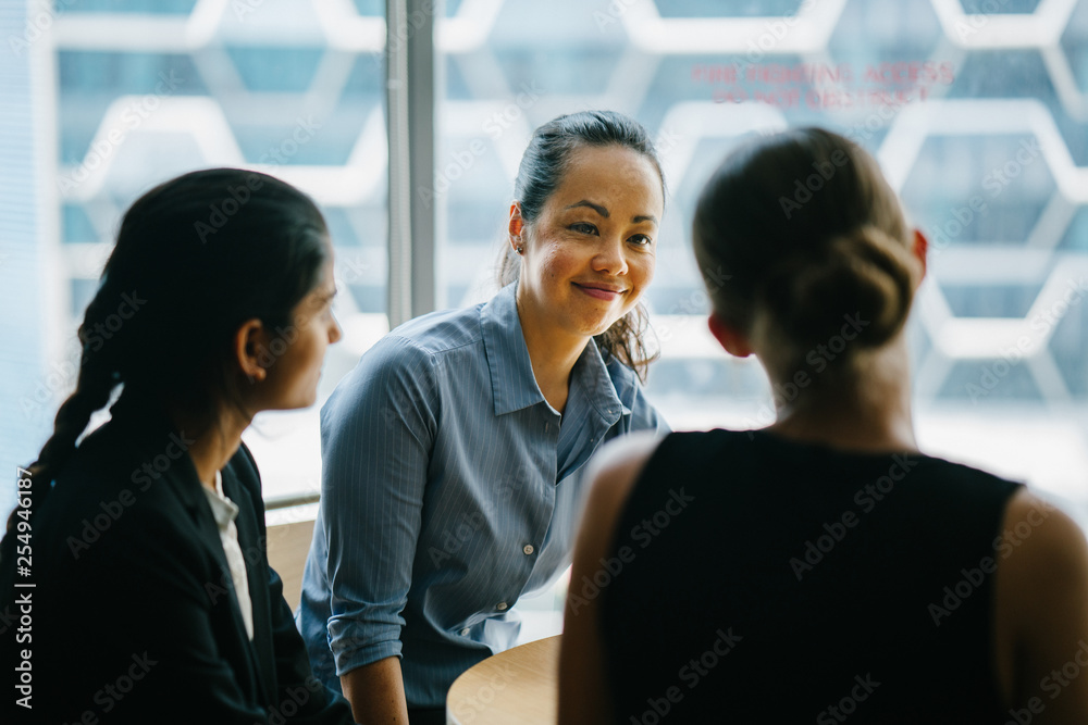 Image of a young Chinese Asian woman manager chatting with her team in ...