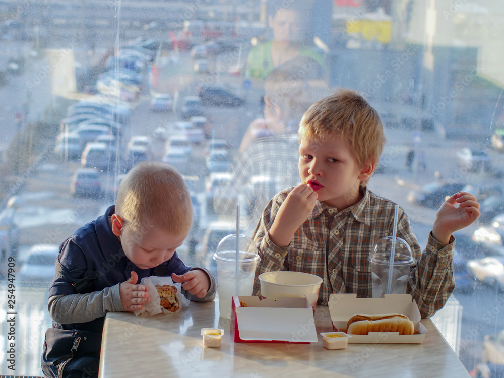 Children have lunch in fast food cafe. Boys drink lemonade and eat ...