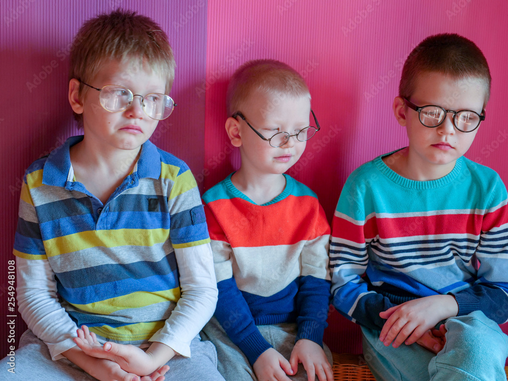 Three brothers in bright colored clothes posing in front of camera with ...
